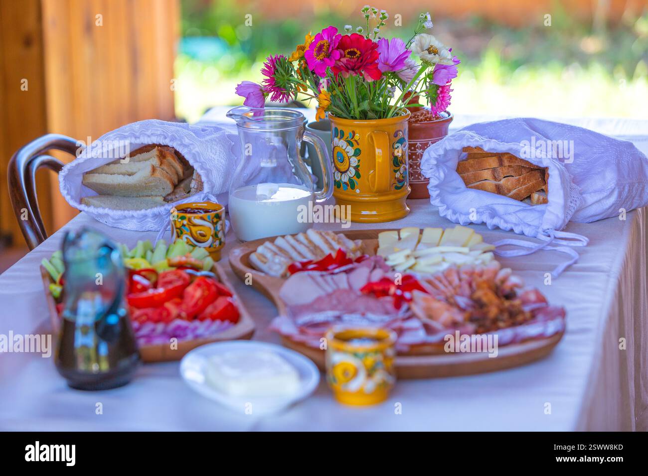 Colorful breakfast spread featuring fresh bread, milk, vegetables ...