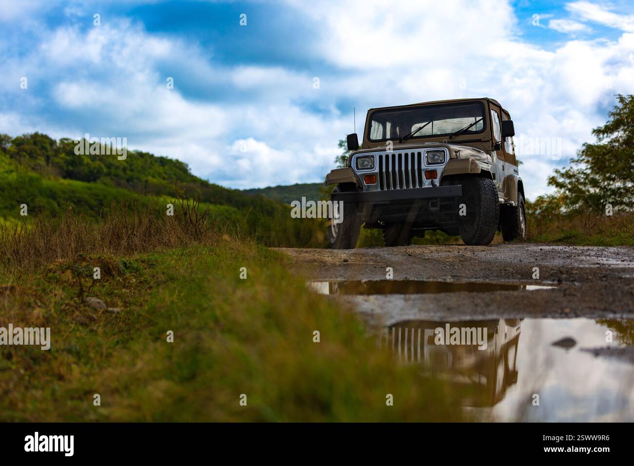 A rugged off-road vehicle parked on a rural road near green hills and ...