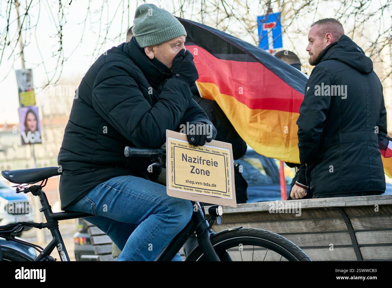 22 February 2025, Berlin: A lone counter-demonstrator sits on his ...