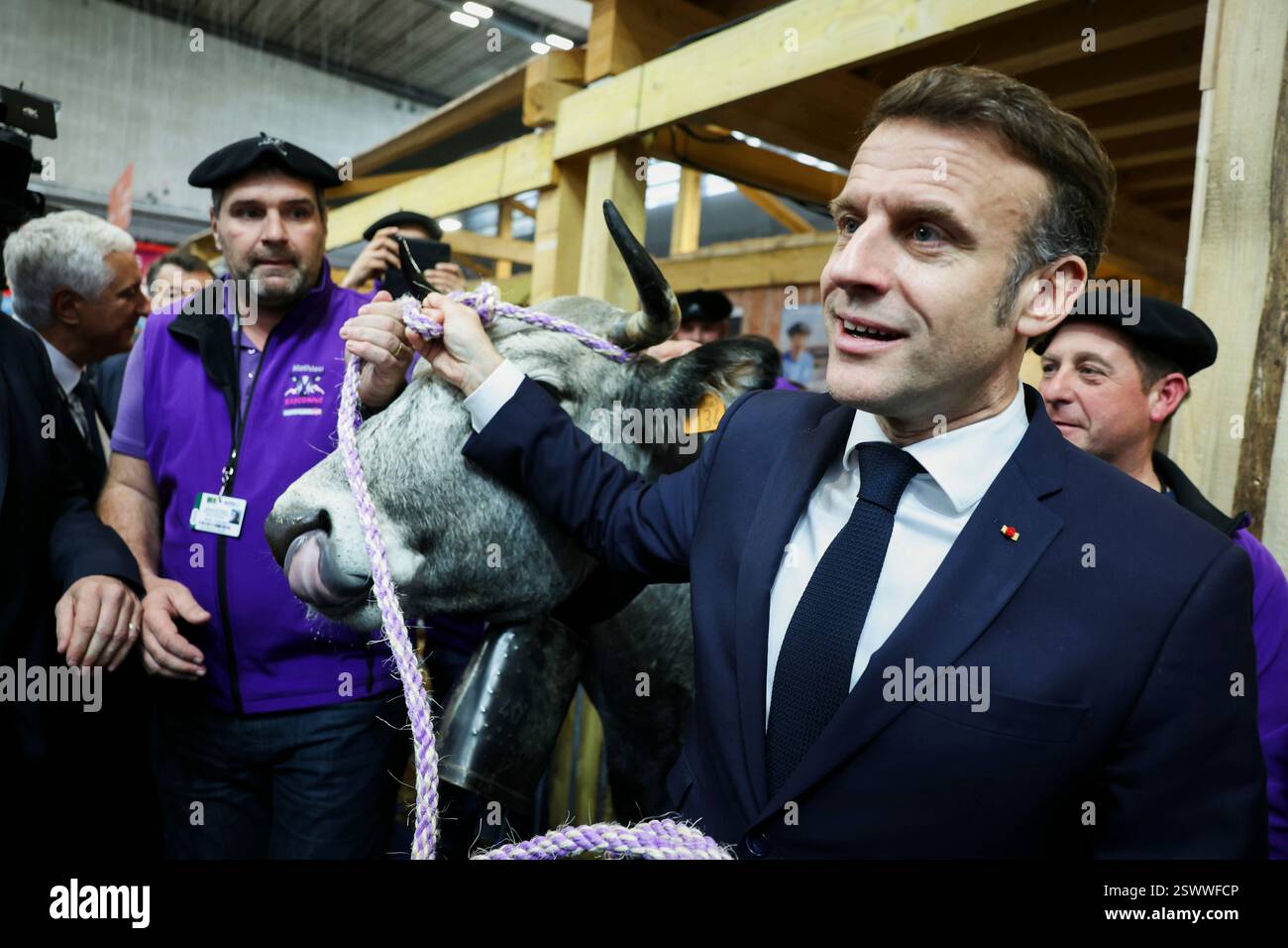 France's President Emmanuel Macron holds the rope of a cow as he visits ...