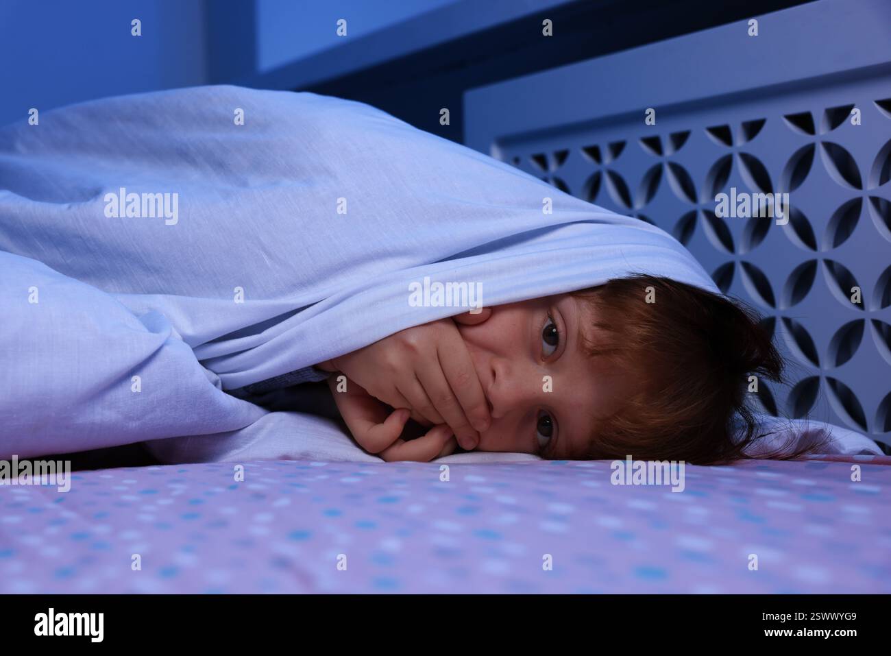 Afraid boy under blanket on bed at night Stock Photo - Alamy