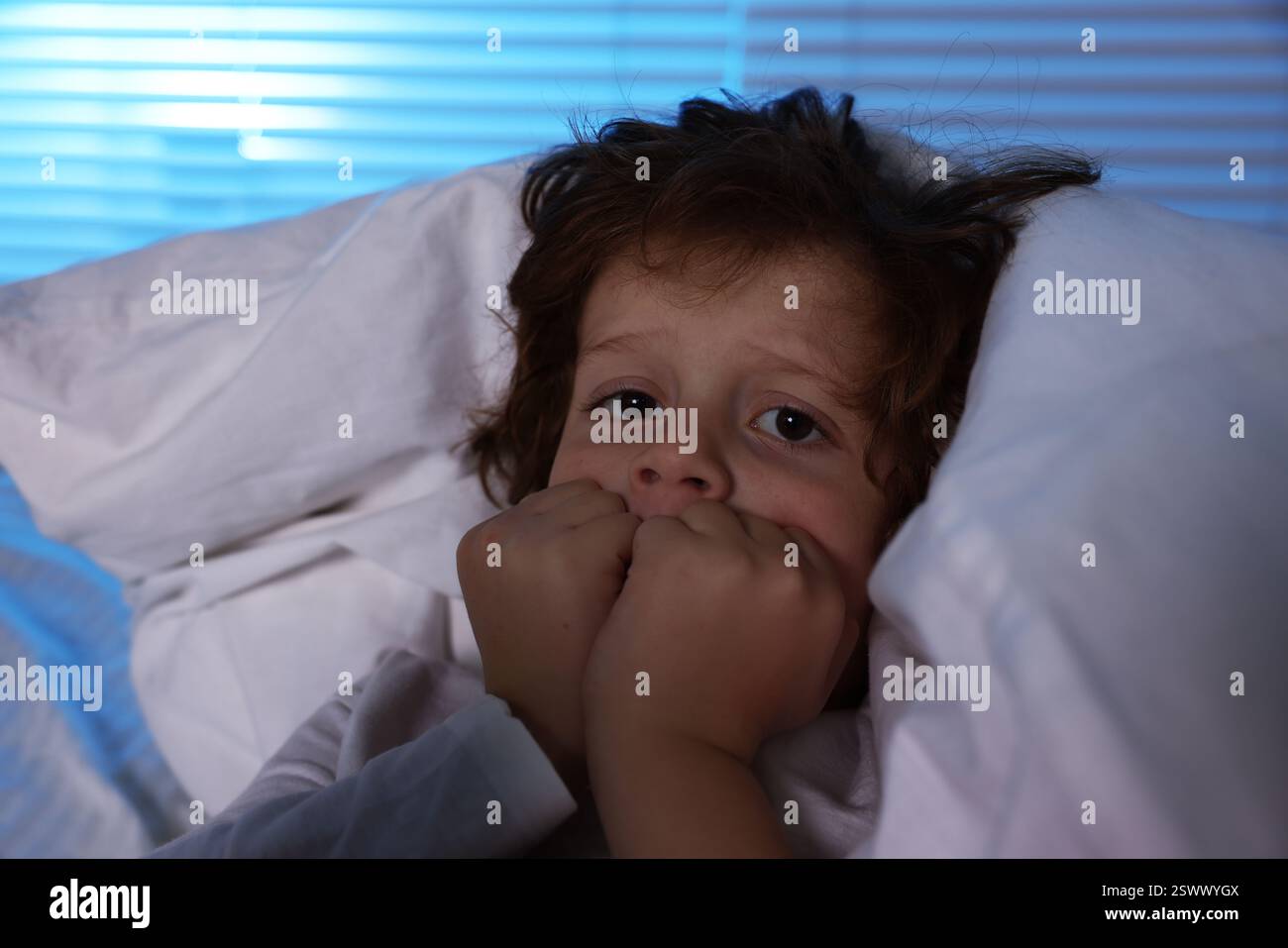 Scared boy under duvet in bed at night Stock Photo - Alamy