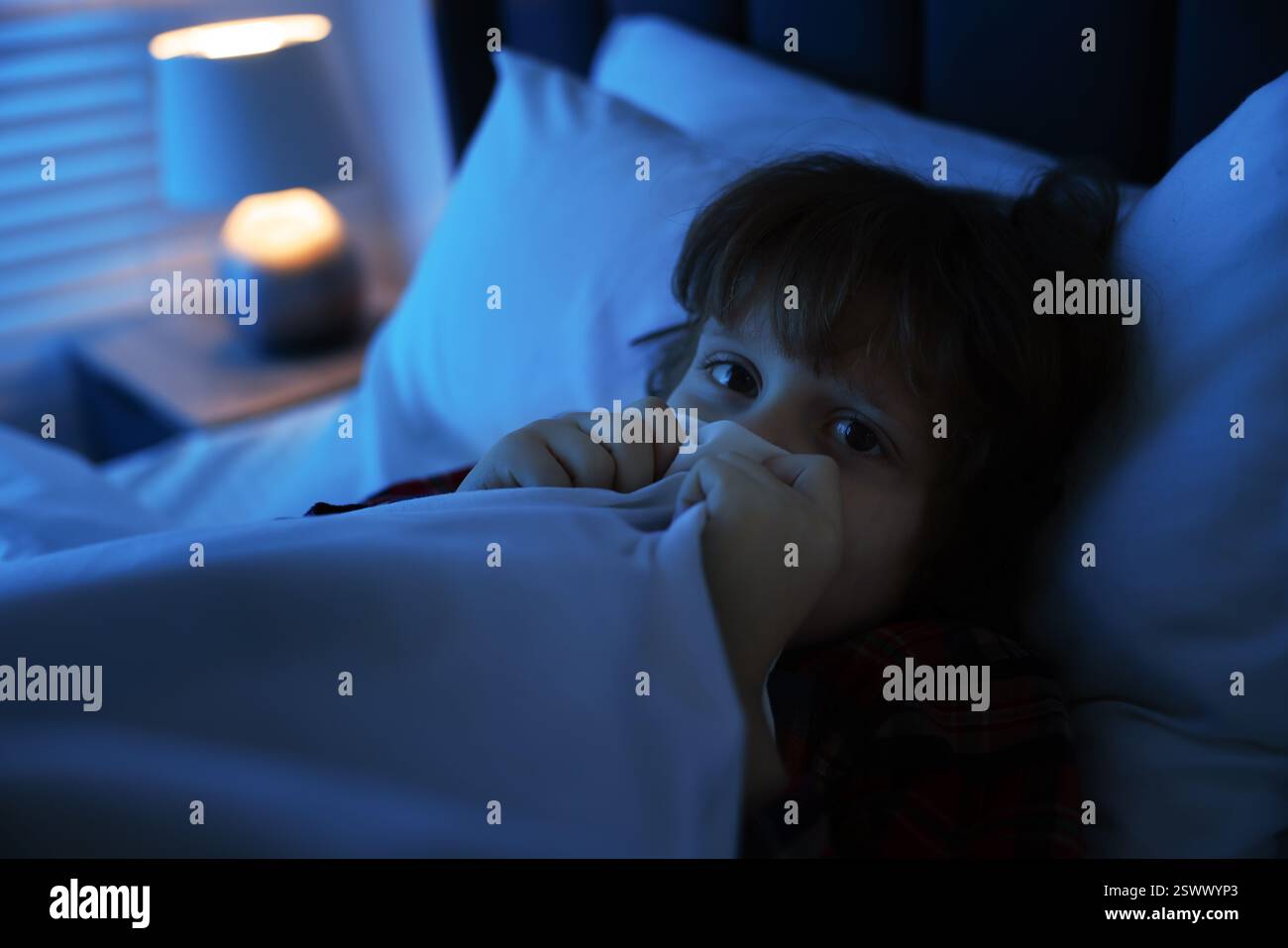 Scared boy hiding under duvet in bed at night Stock Photo - Alamy