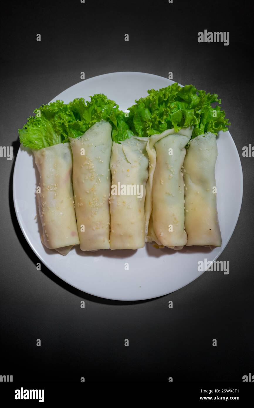 A plate of freshly made spring rolls with sesame seeds, ready to be ...