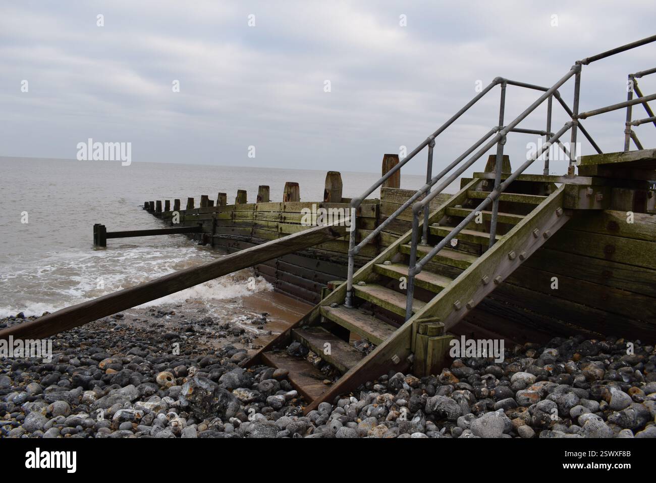 Pebbled beach with wood breaker and stairs Stock Photo - Alamy