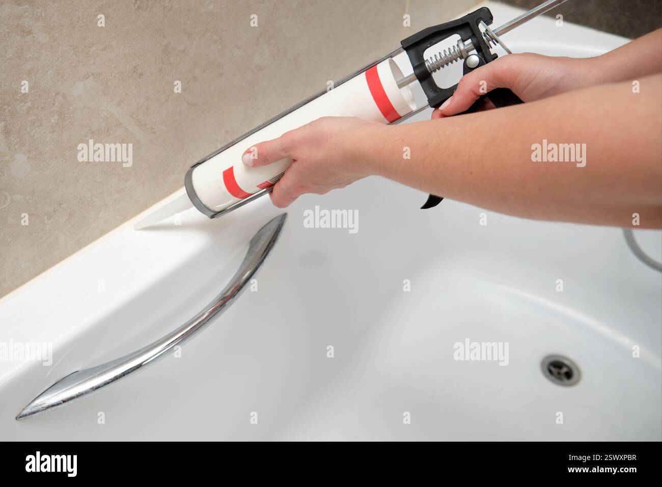 Hand applying sealant to bathtub corner using caulking gun. Home ...