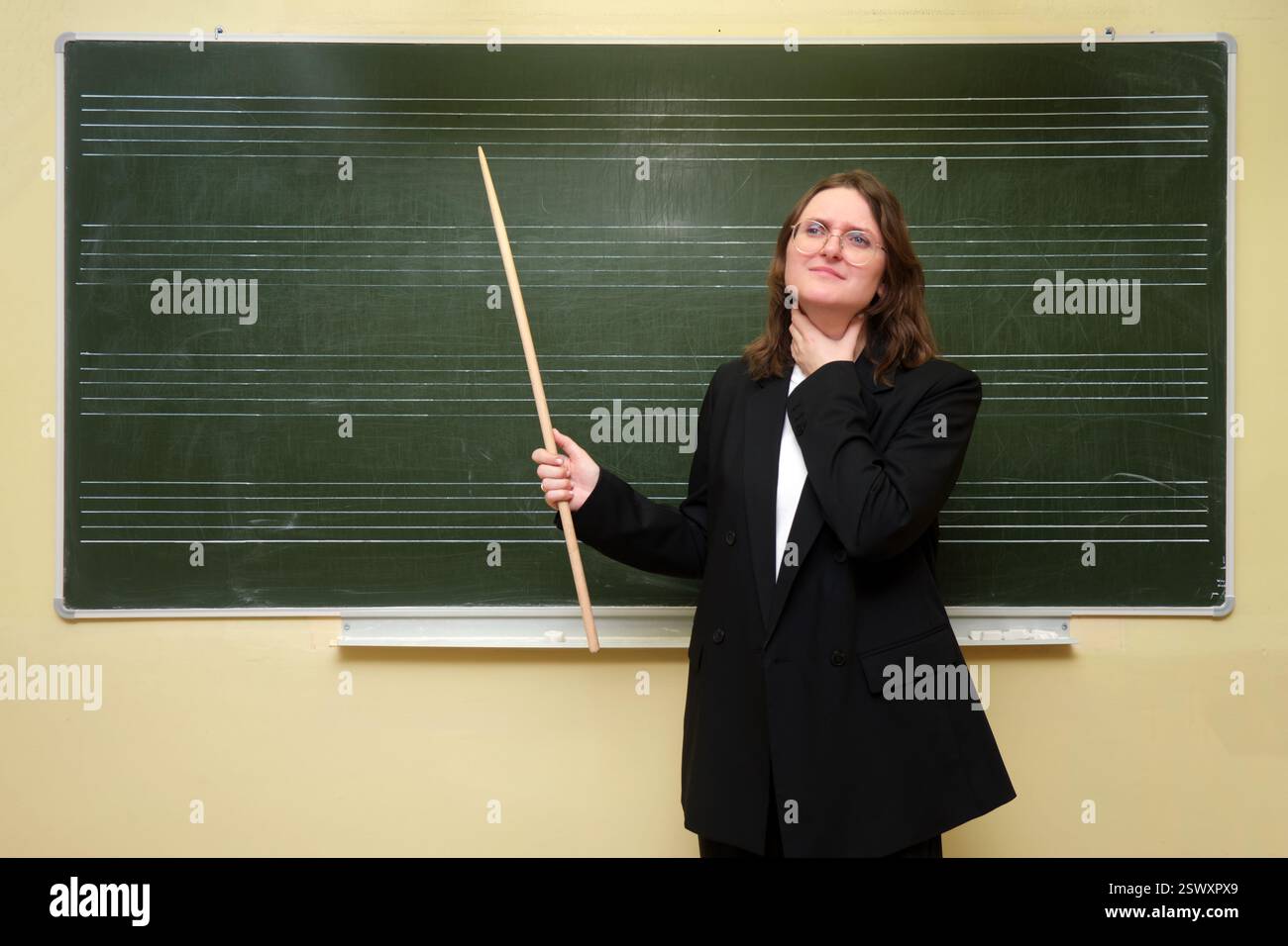 The ill teacher, holding her neck in pain from a sore throat, stands in ...