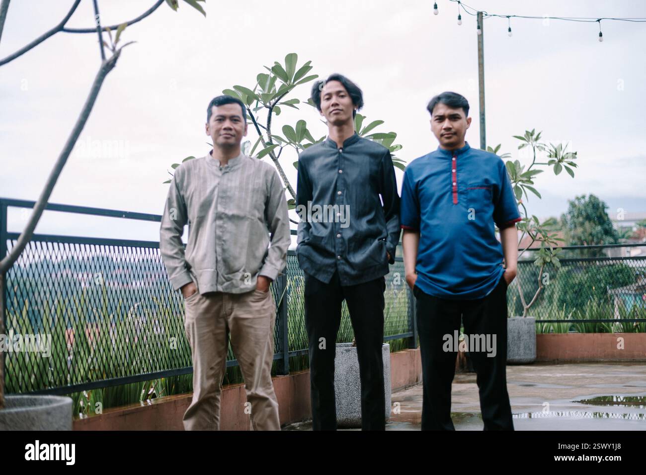 Three Indonesian men wearing batik shirts pose for a portrait on a ...