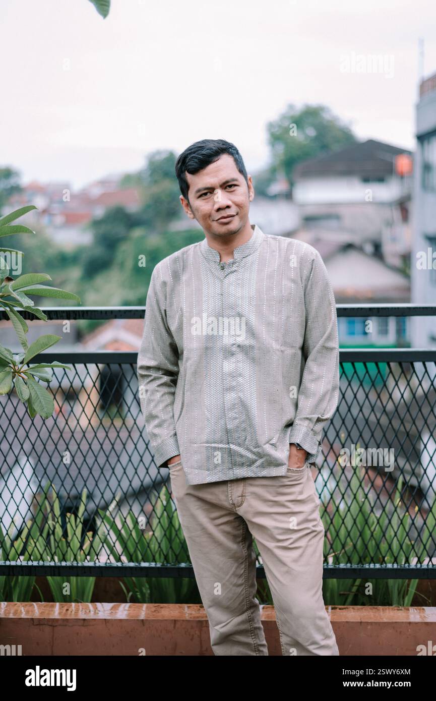 A confident Southeast Asian man in casual attire poses on an urban ...