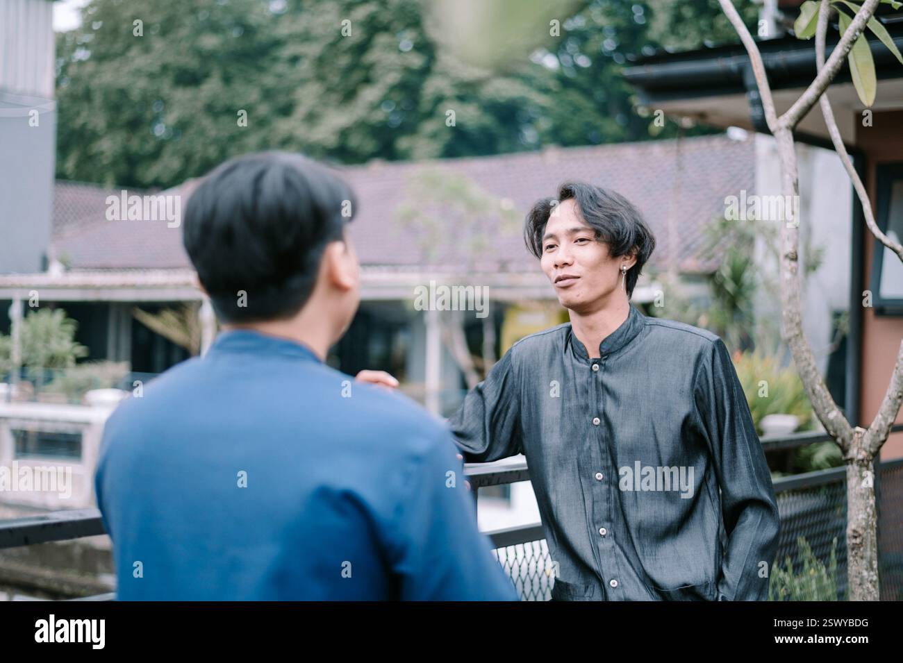 Two young men engage in a casual and friendly conversation outdoors on ...