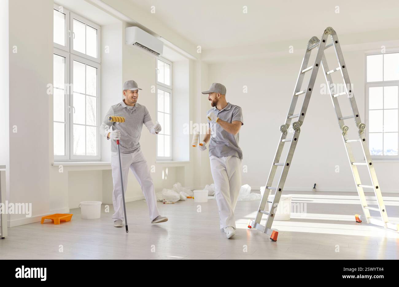 Two cheerful painters having fun, dancing with painting tools, taking ...