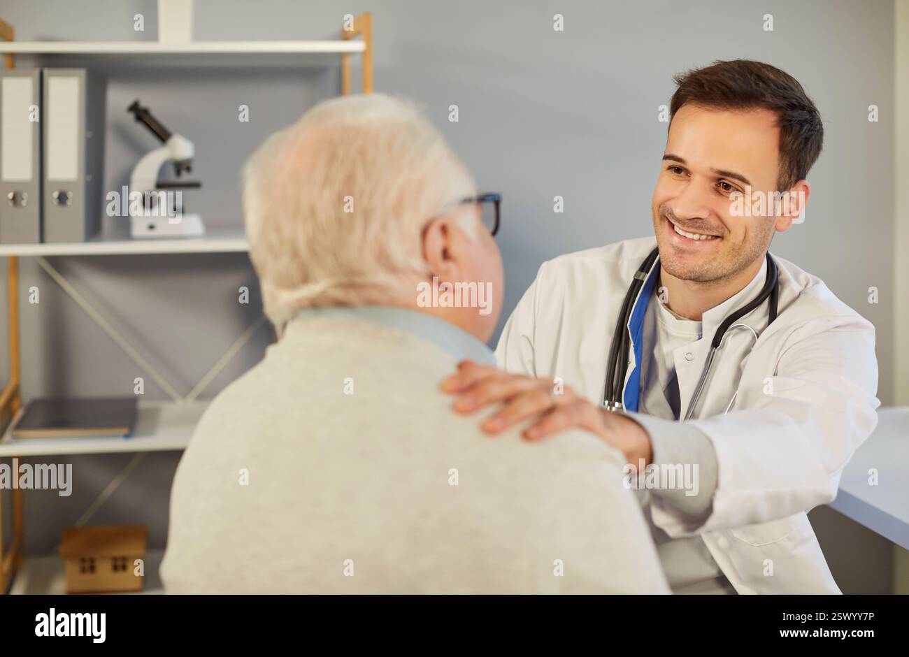 Friendly smiling doctor comforting patient during consultation ...