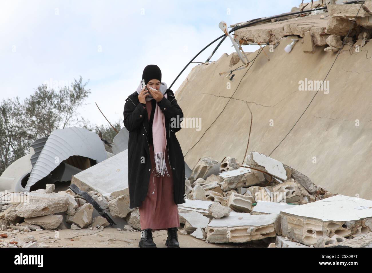Mays Al Jabal. 22nd Feb, 2025. A woman makes a phone call among debris ...