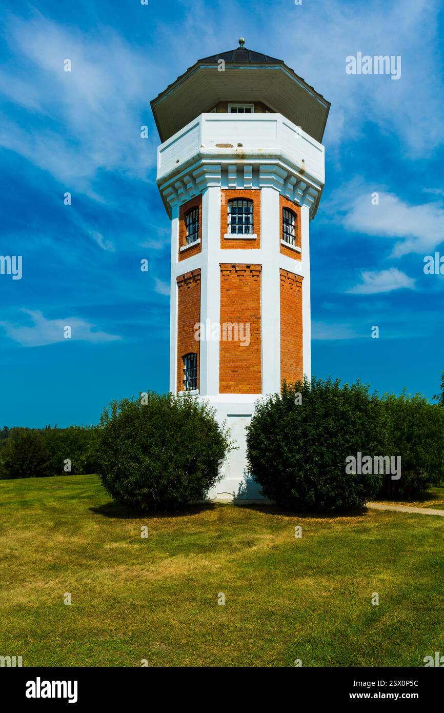 Tall brick tower with a white roof. The tower is surrounded by grass ...