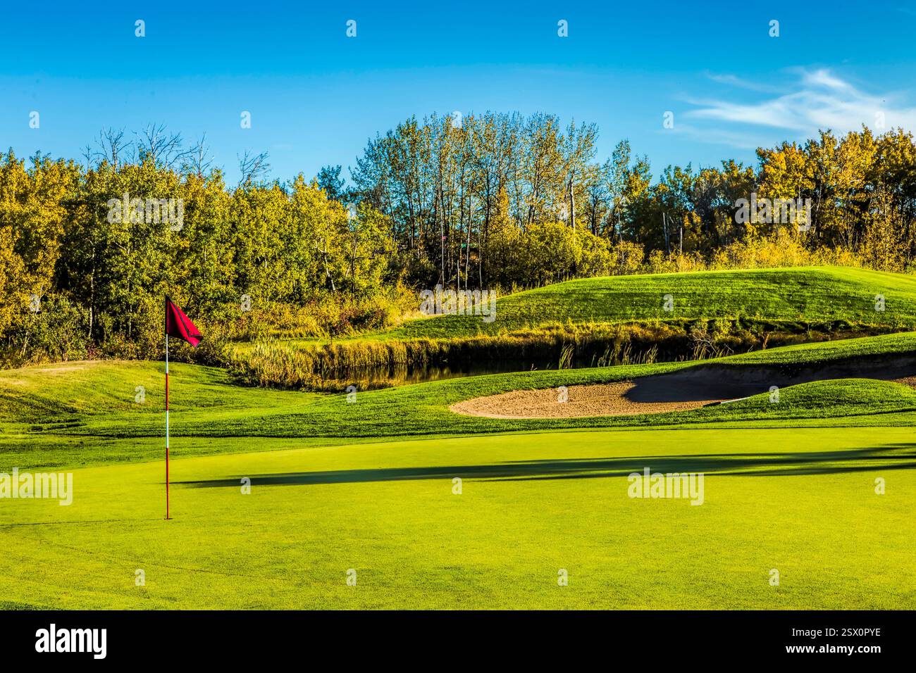 Golf course with a red flag on the green grass. The flag is on the ...