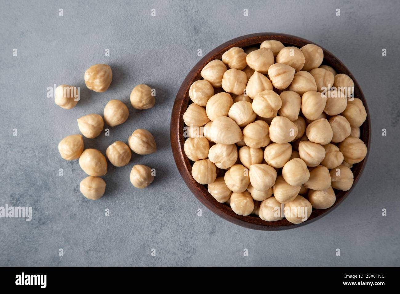 Top view of a bowl full of peeled hazelnuts kernel on concrete ...