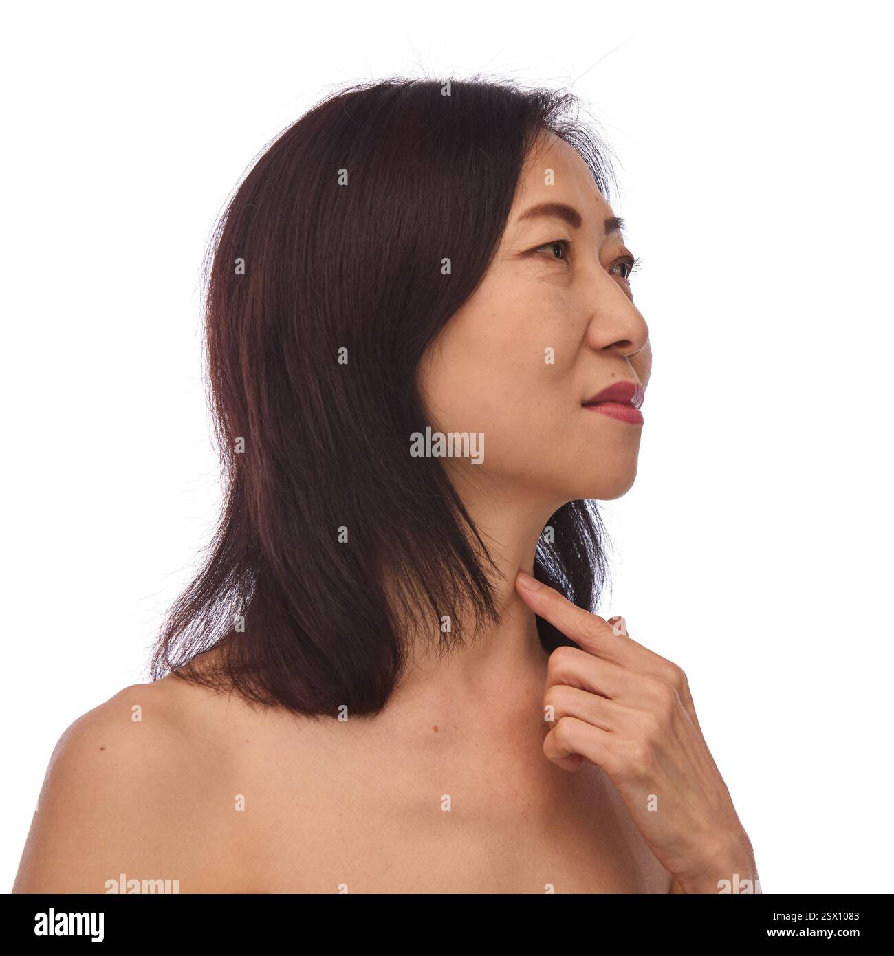 Double chin reduction. Mature Korean woman in her 60s touching her chin ...