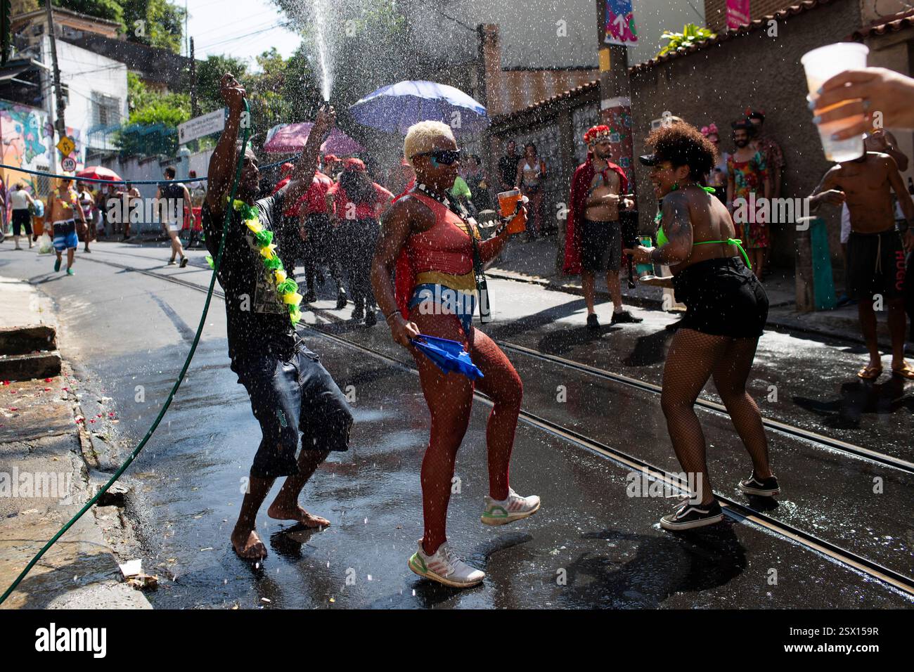 A reveler sprays water on fellow merry makers cooling them off during ...