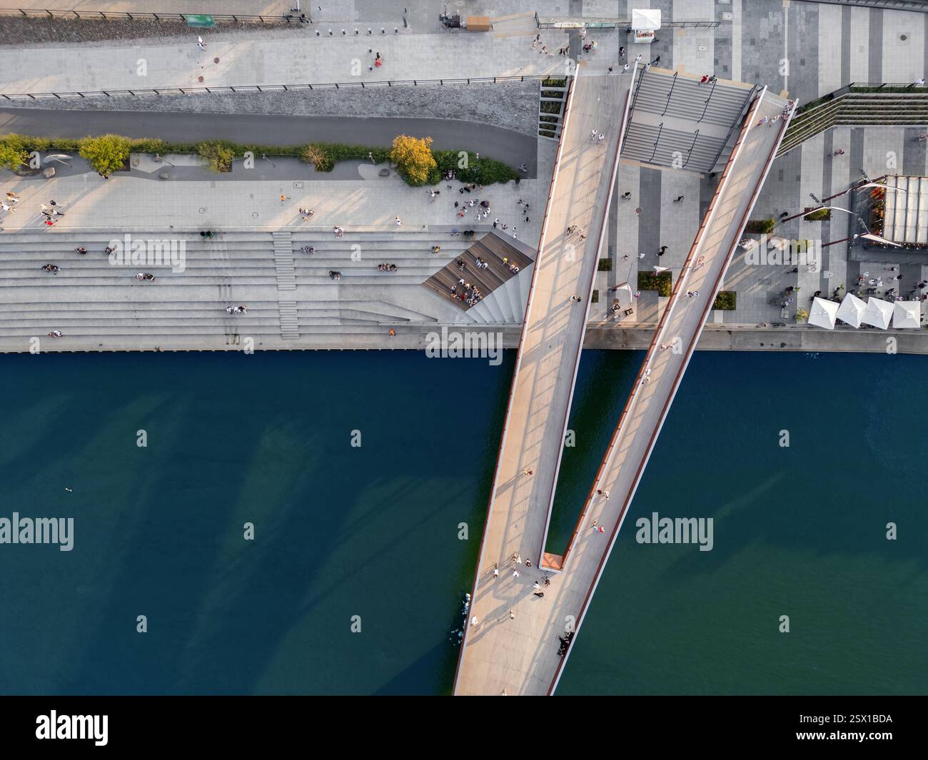 pedestrian bridge over blue Vistula river, people walking at shore and ...