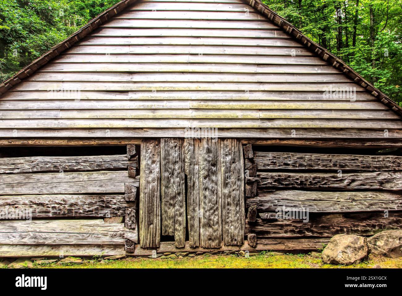 Large wooden building with a slanted roof. The roof is covered in moss ...