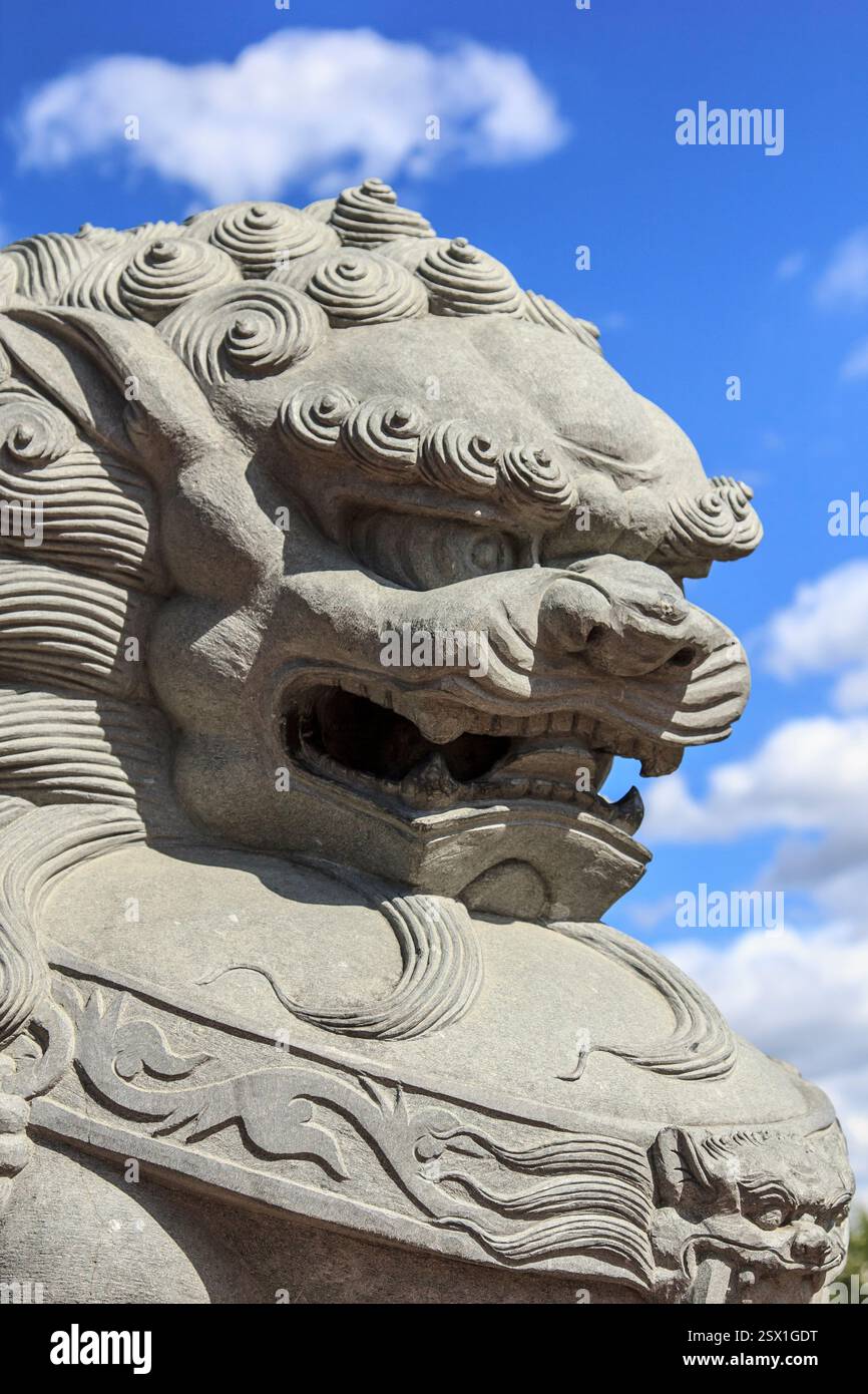 Stone statue of a dragon with a mouth open. The statue is on a cloudy day. The sky is blue Stock ...