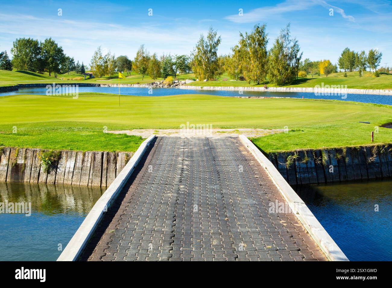 Bridge over a body of water with a golf course in the background. The ...