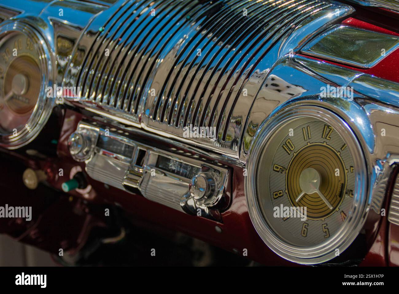 Chrome trim on the dash of a classic car. A large clock matches the ...