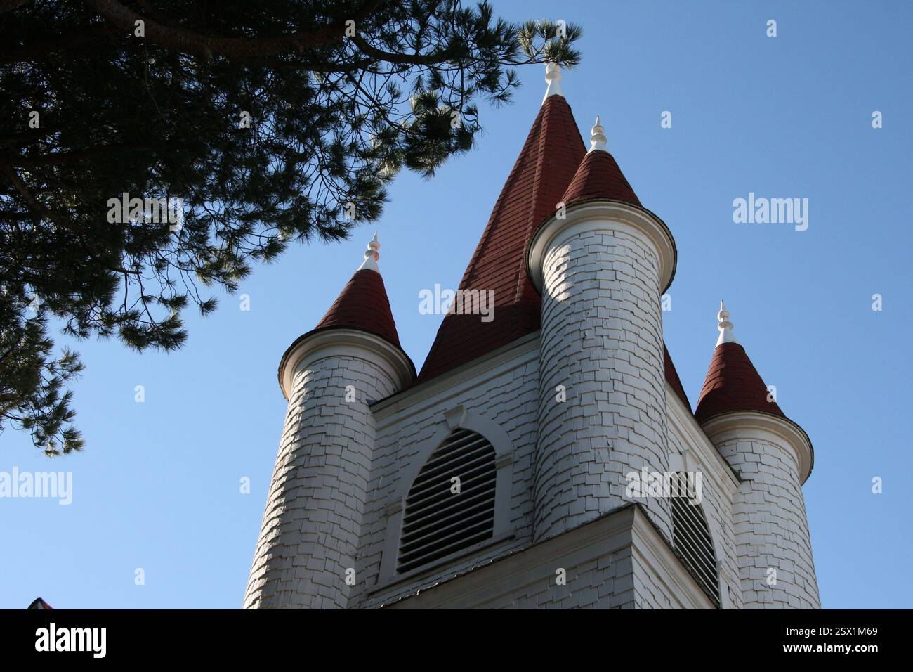 A church steeple with round towers at the corners with pointed roofs ...