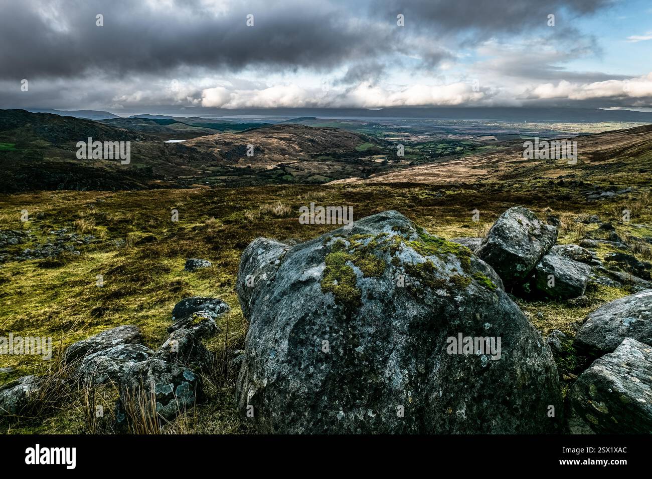 Dark grey rocks of varying sizes are piled on a hillside. A view of a ...