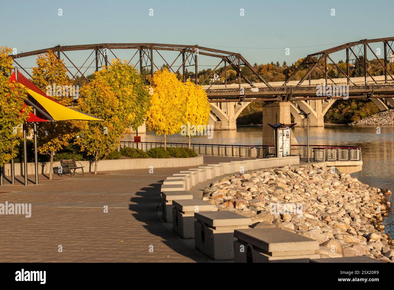 Bridge spans a river with a park on the other side. The park has ...