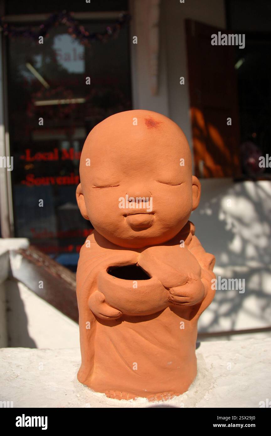 Terracotta statue of a child monk holding a begging bowl, with closed ...