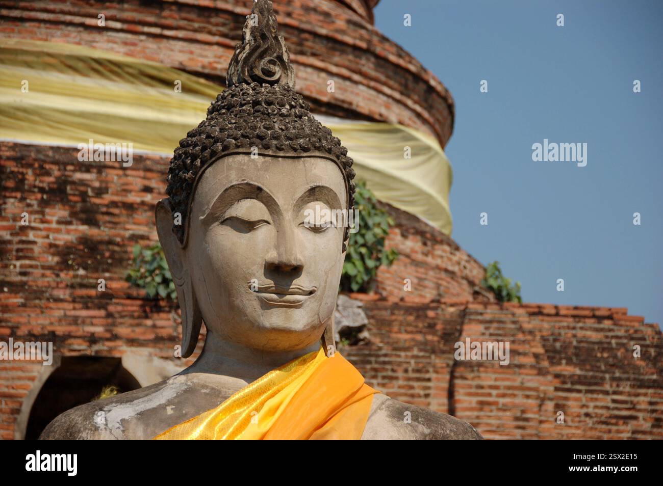 sacred Buddha stone statue in Ayutthaya, Thailand, draped with orange ...