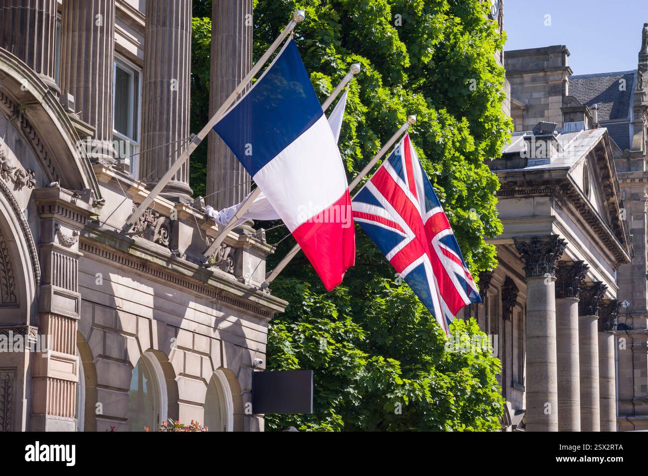 French flag and Union Jack flying side by side on flagpoles outside a ...