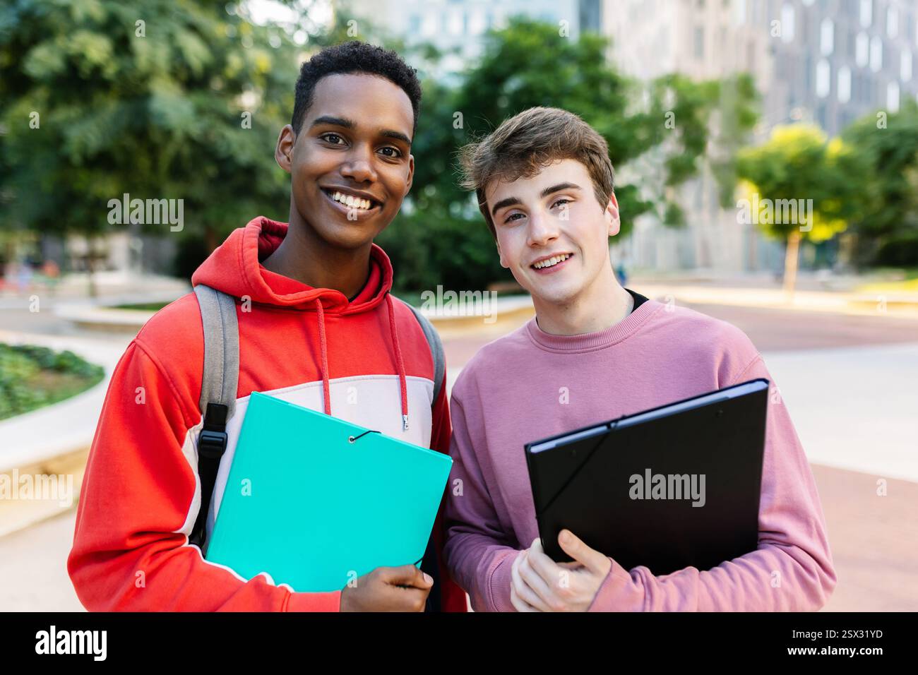 Two young university male students smiling together at camera on campus ...