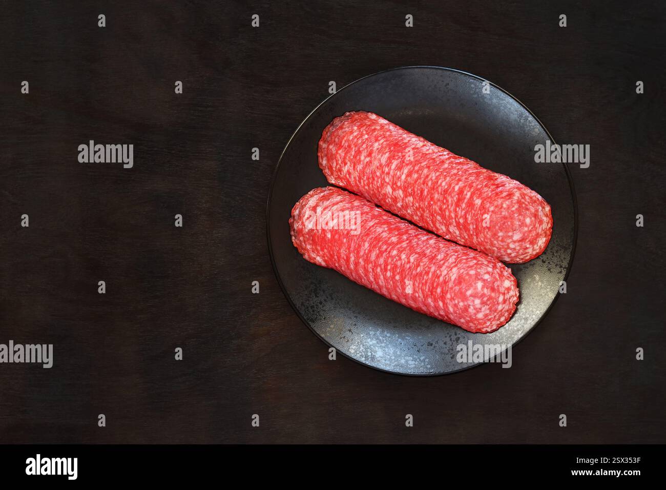 Salami sausage in a black plate, top view. Thinly sliced salami sausage ...