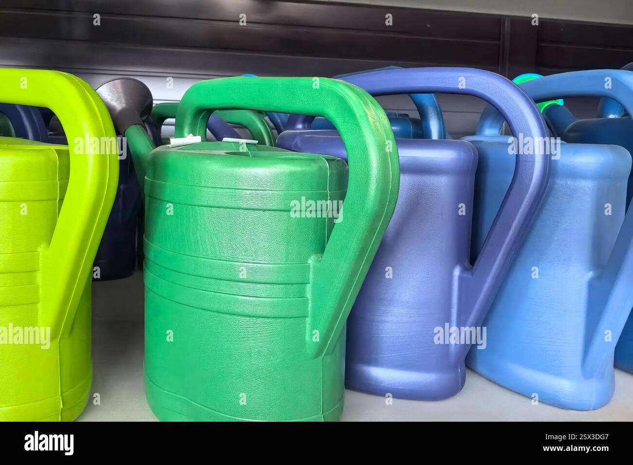 Brightly colored watering cans in green and blue sit together on a ...