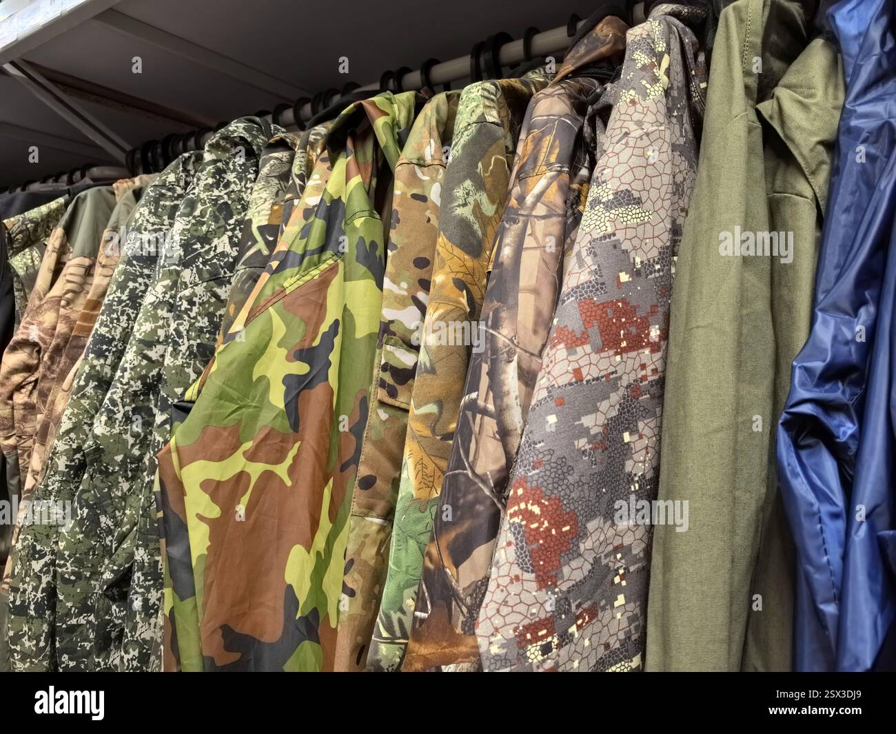 A collection of various camouflage patterns hangs neatly on racks ...