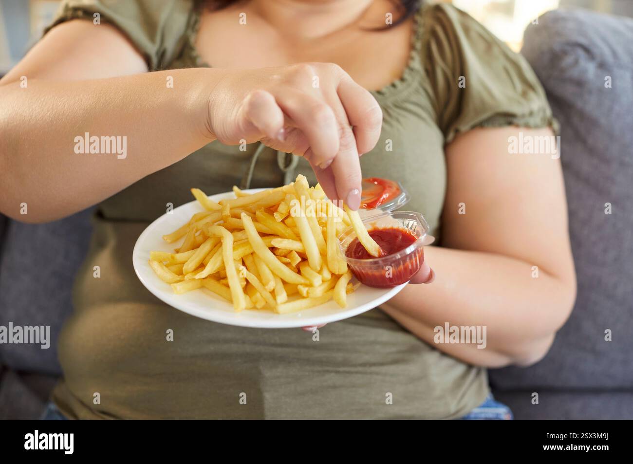Overweight woman is eating unhealthy but delicious French fries with ...