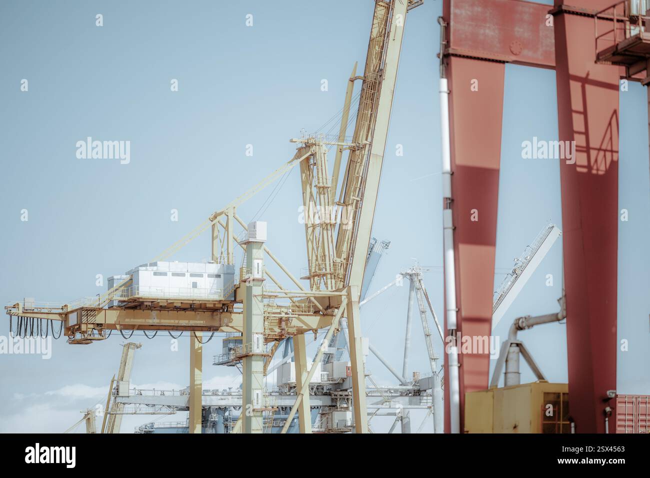 A telephoto shot of industrial shipping port with large yellow and red ...