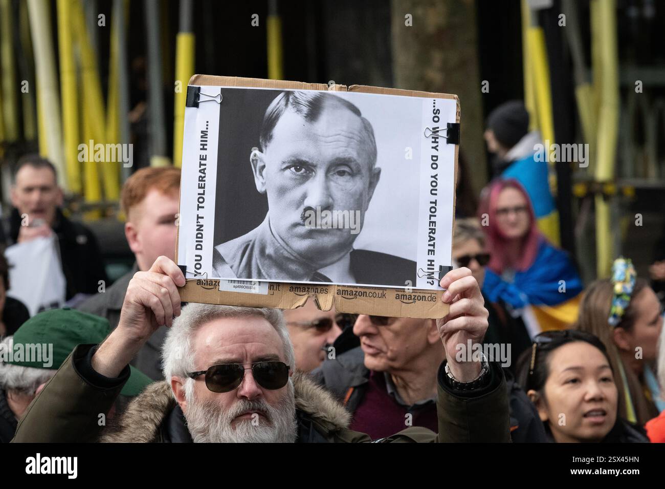 London, UK. 22 February, 2025. A man holds aloft a composite photo ...