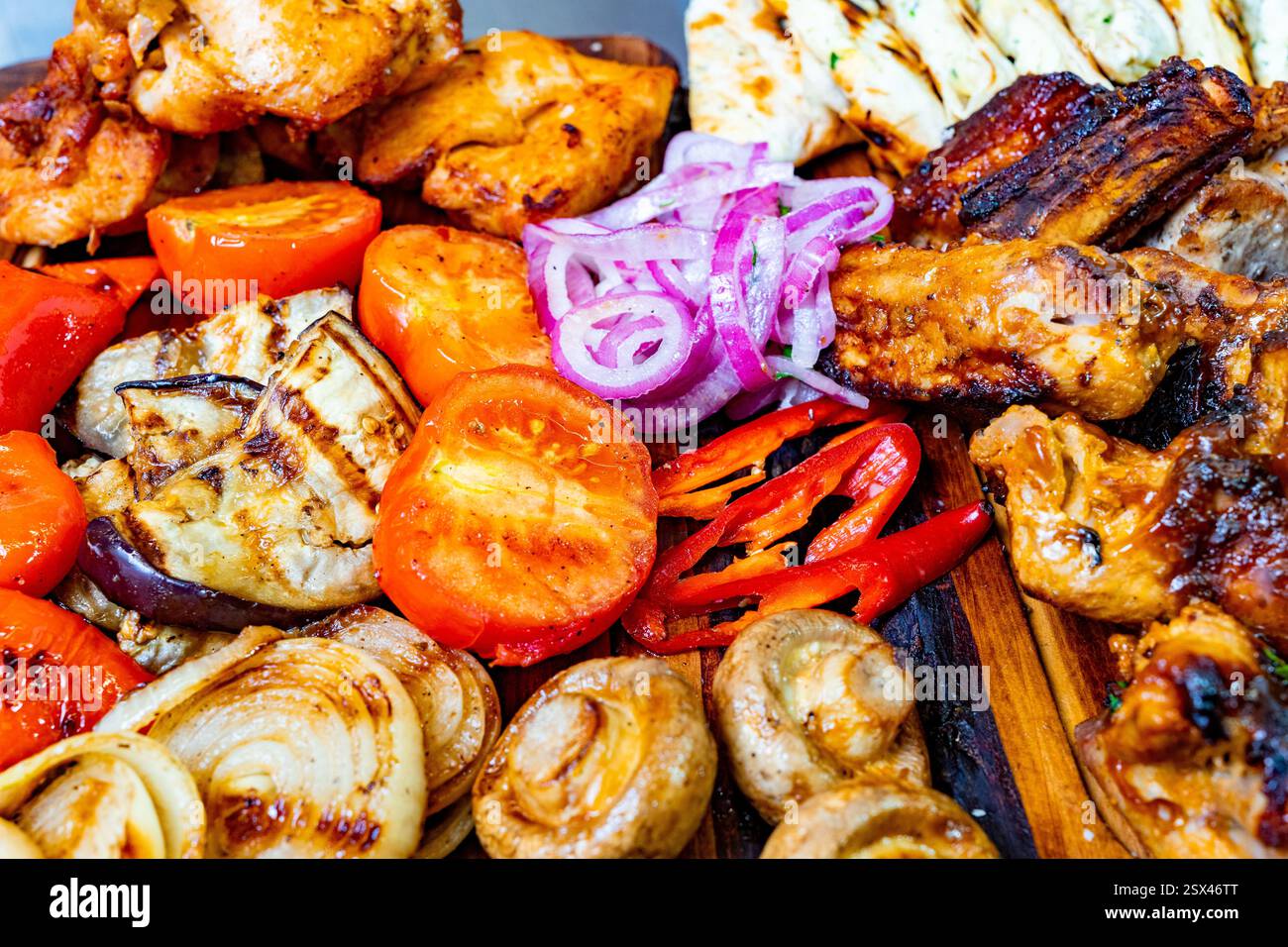 A wooden platter displays an array of grilled meats, colorful ...