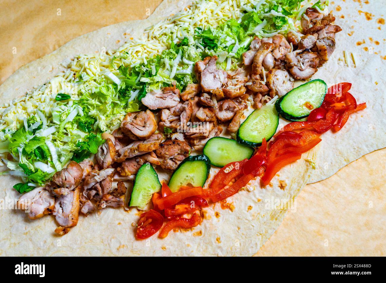 A delicious wrap is being prepared with layers of grilled chicken ...