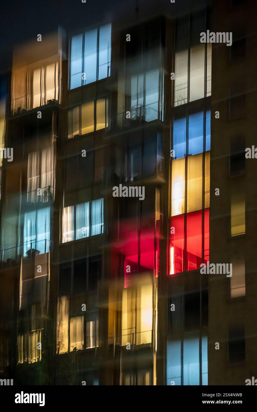 Apartment block with lighted windows in different colours at night ...