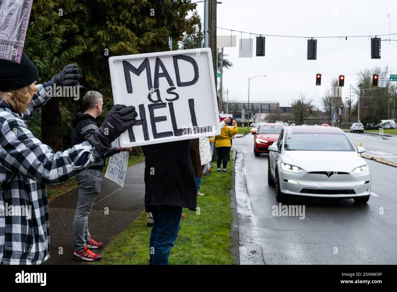 Seattle, USA. 22 Feb 2025. A Tesla passes by activists at the Tesla ...