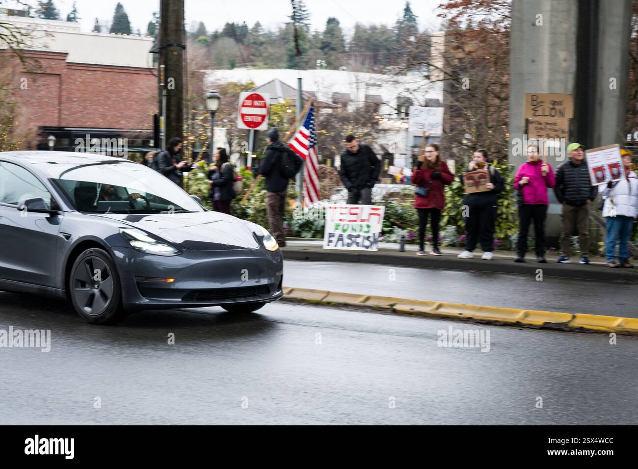 Seattle, USA. 22 Feb 2025. A Tesla passes by activists at the Tesla ...
