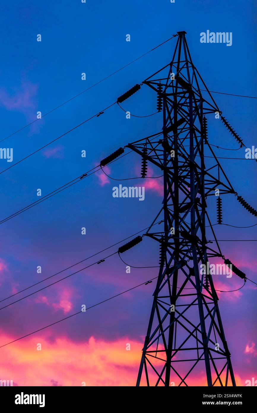 Tall power tower with a purple sky in the background. The tower is lit ...