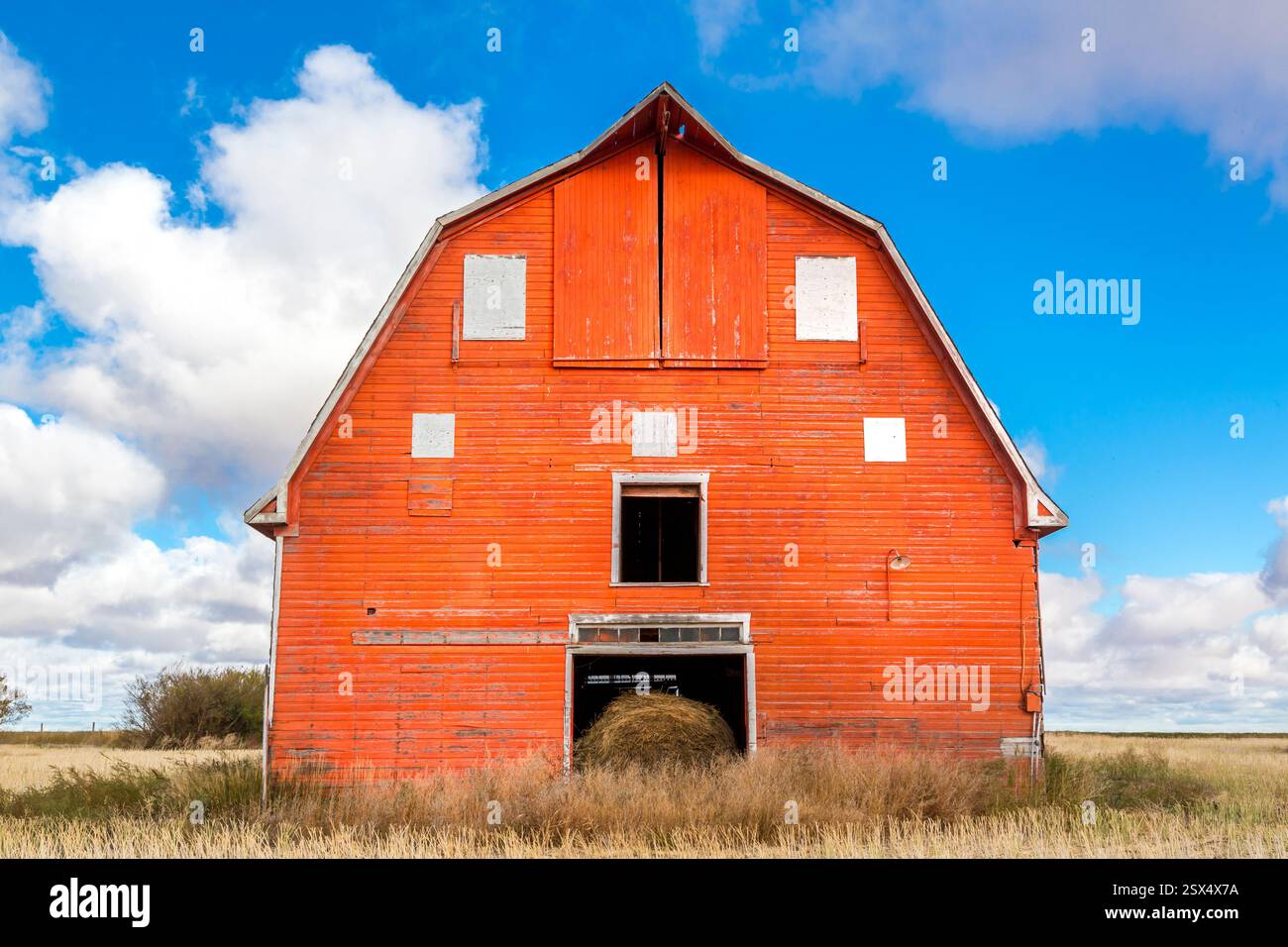 Red barn with a hay bale inside. The barn is empty and has a lot of ...