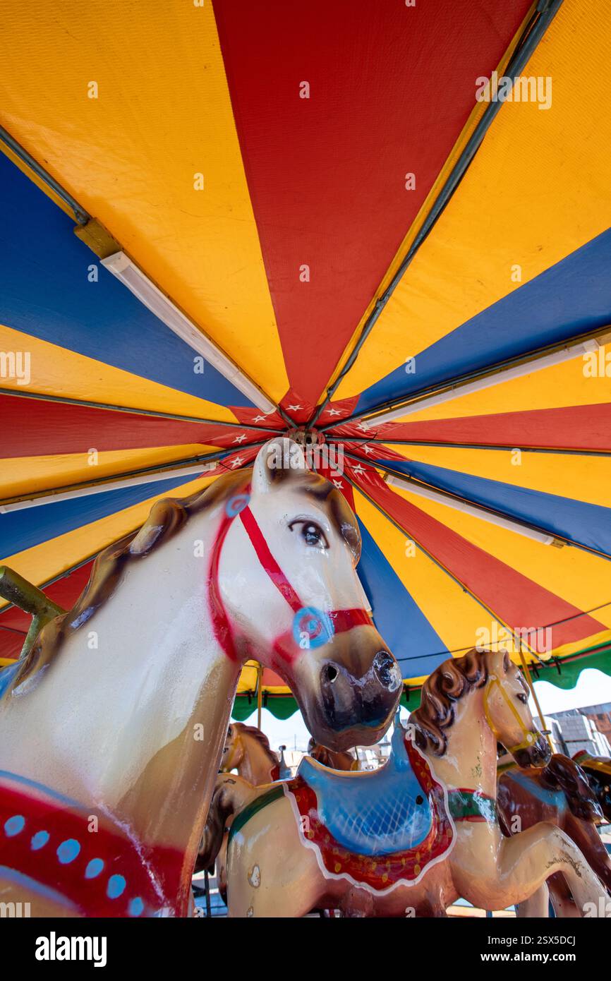 Carousel in an amusement park with the multicolored tent, on ...
