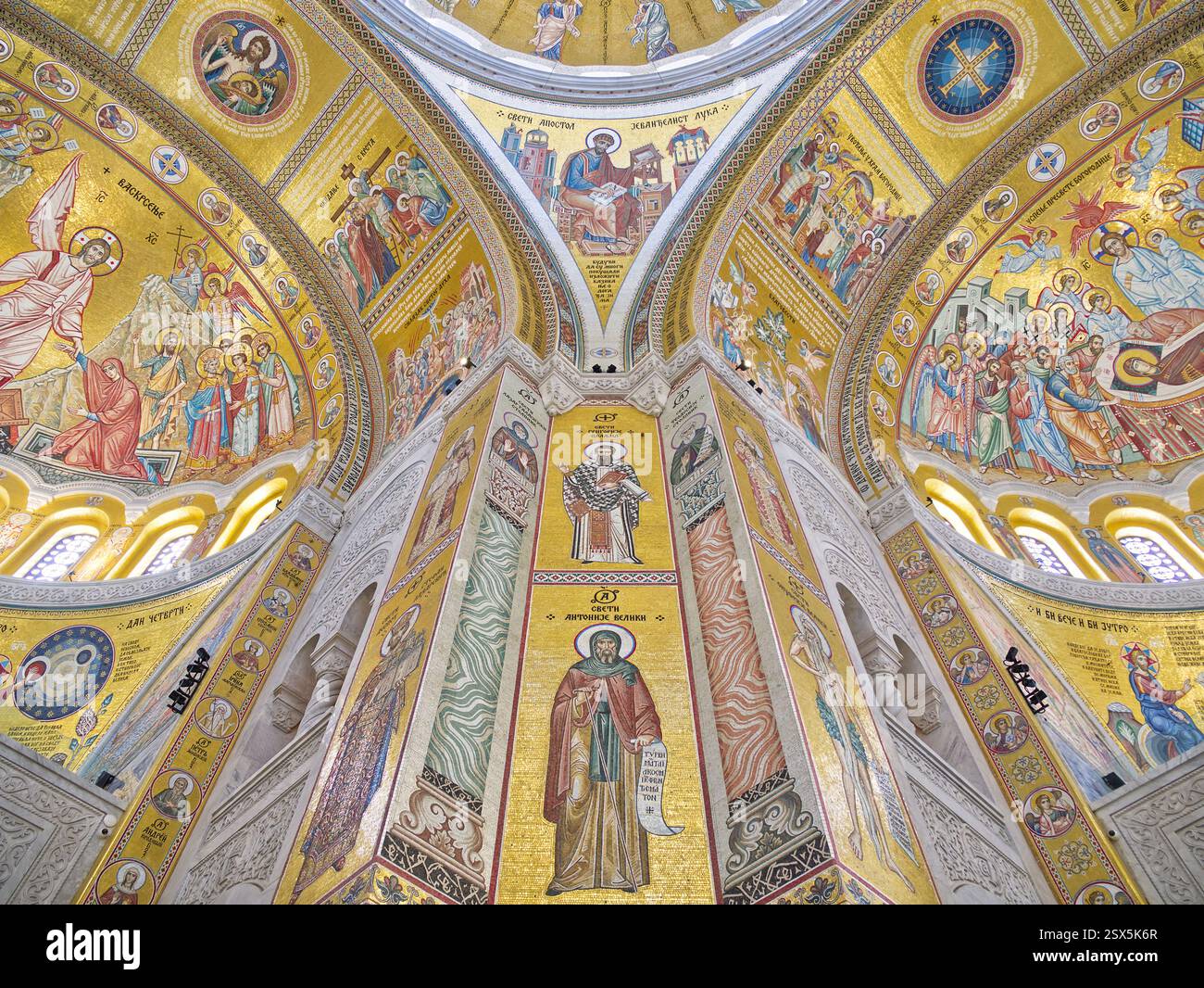 Richly decorated church interior with golden mosaics depicting religious scenes and figures ...