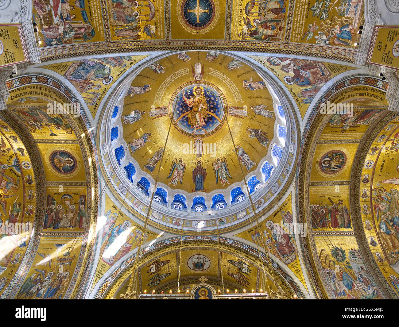 Intricate religious frescoes and mosaics adorn a golden domed ceiling in Byzantine architectural ...